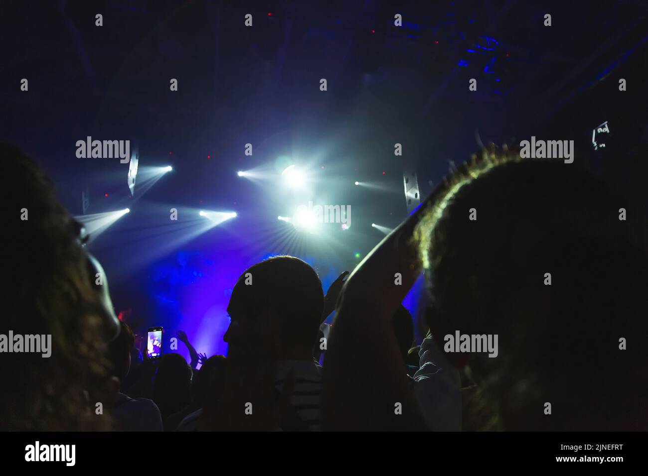 Silhouettes of a concert crowd in front of an illuminated stage in a ...