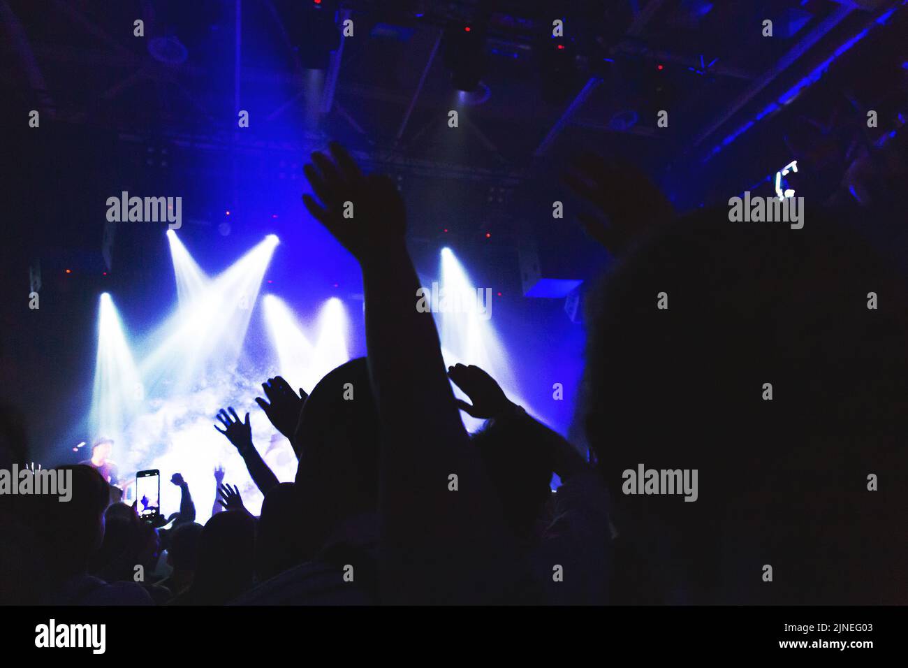 Silhouettes of a concert crowd in front of an illuminated stage in a ...
