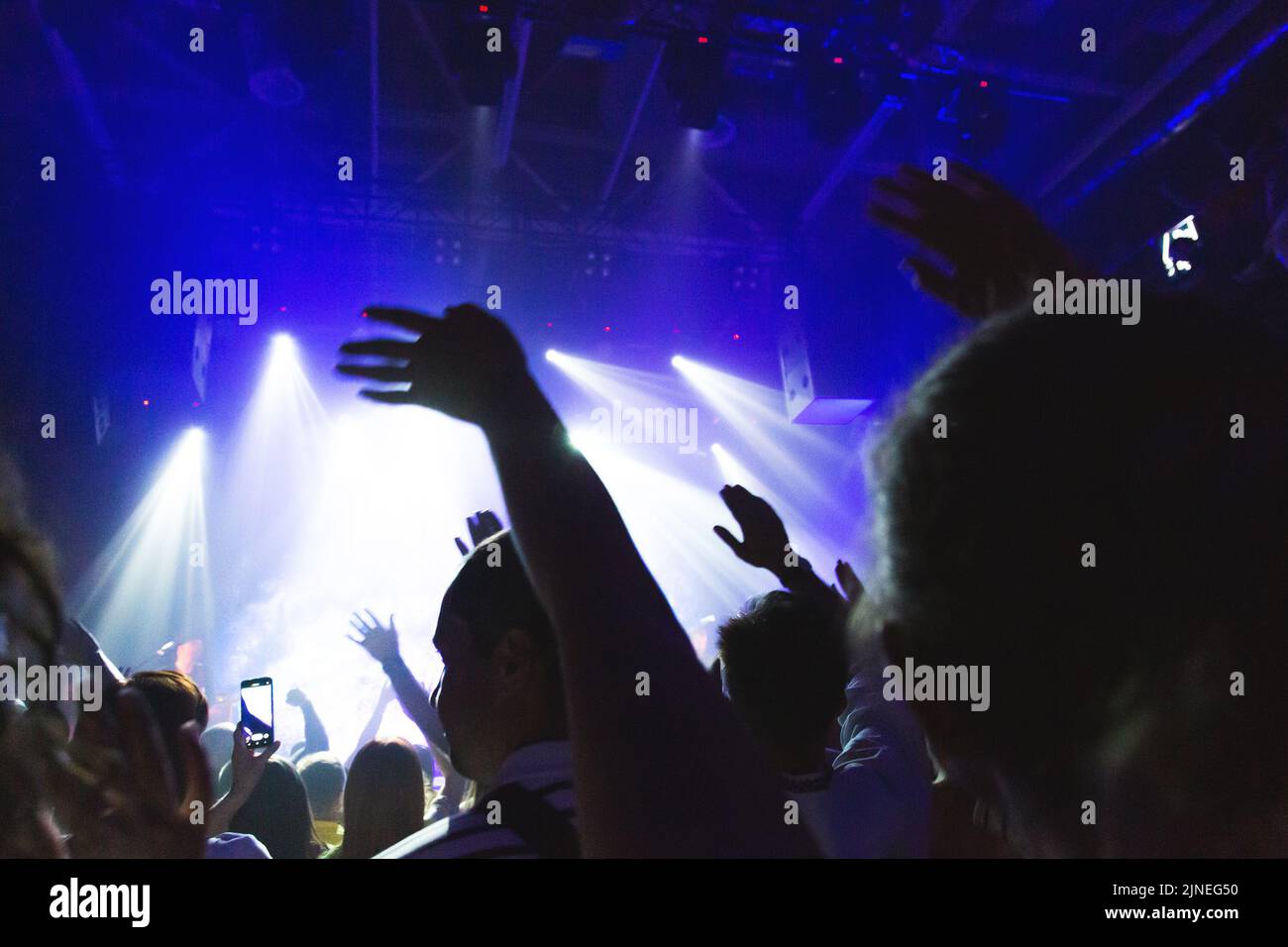 Silhouettes of a concert crowd in front of an illuminated stage in a ...