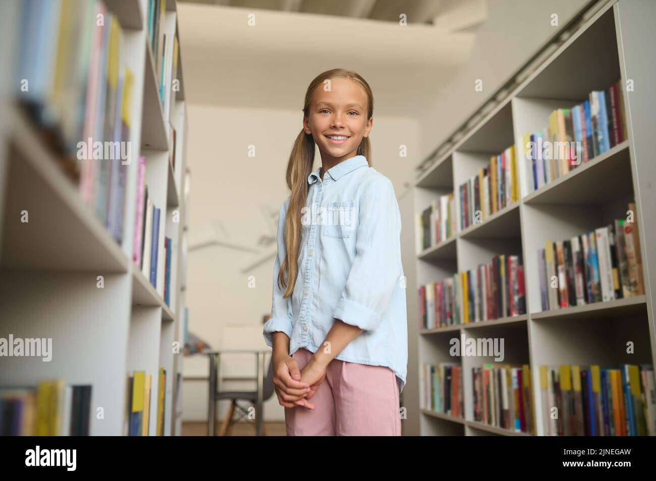 Pleased young lady standing in the school library Stock Photo - Alamy