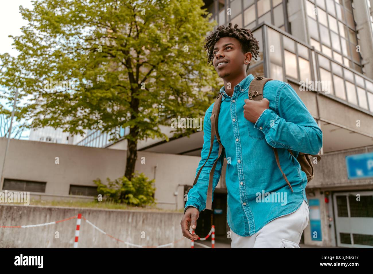 Guy with backpack confidently walking down street Stock Photo - Alamy
