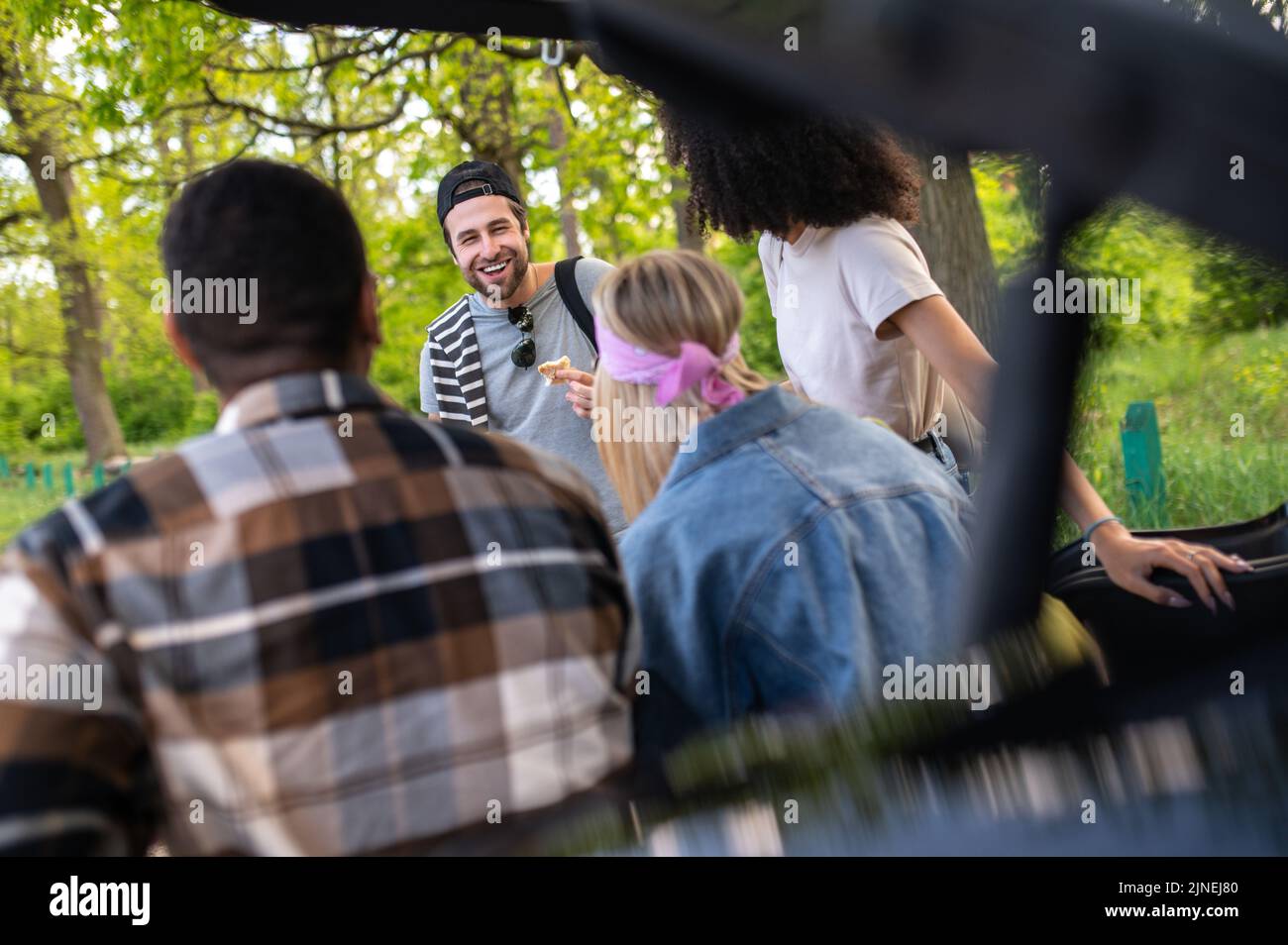 Group of young people sitting near the acr and talking Stock Photo - Alamy