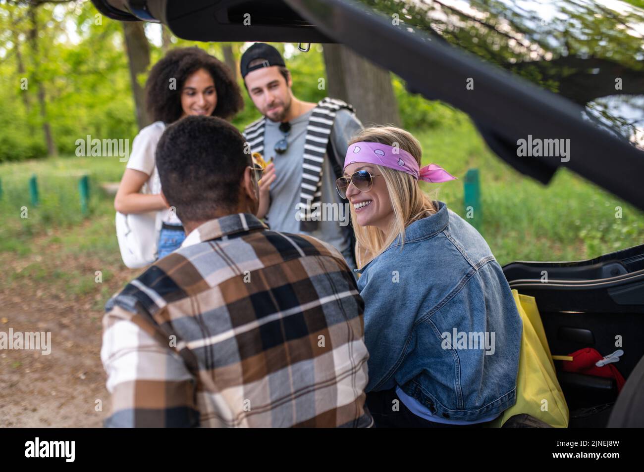 Group of young people sitting near the acr and talking Stock Photo - Alamy