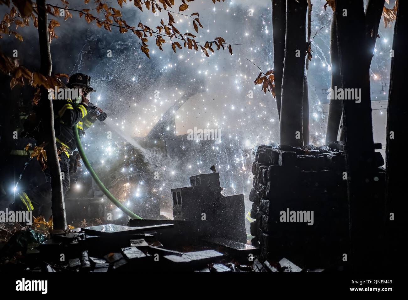 A firefighter using a hose to extinguish a fire in the engine ...