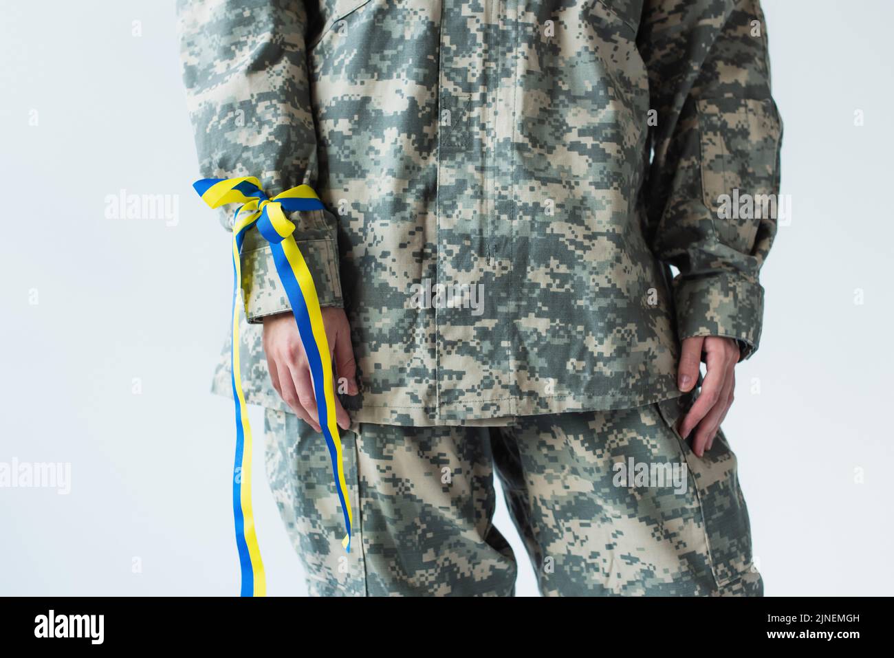 Cropped view of soldier in uniform with blue and yellow ribbon on hand ...