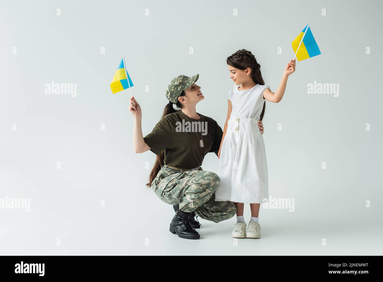 Side view of smiling parent in military uniform and child holding ...