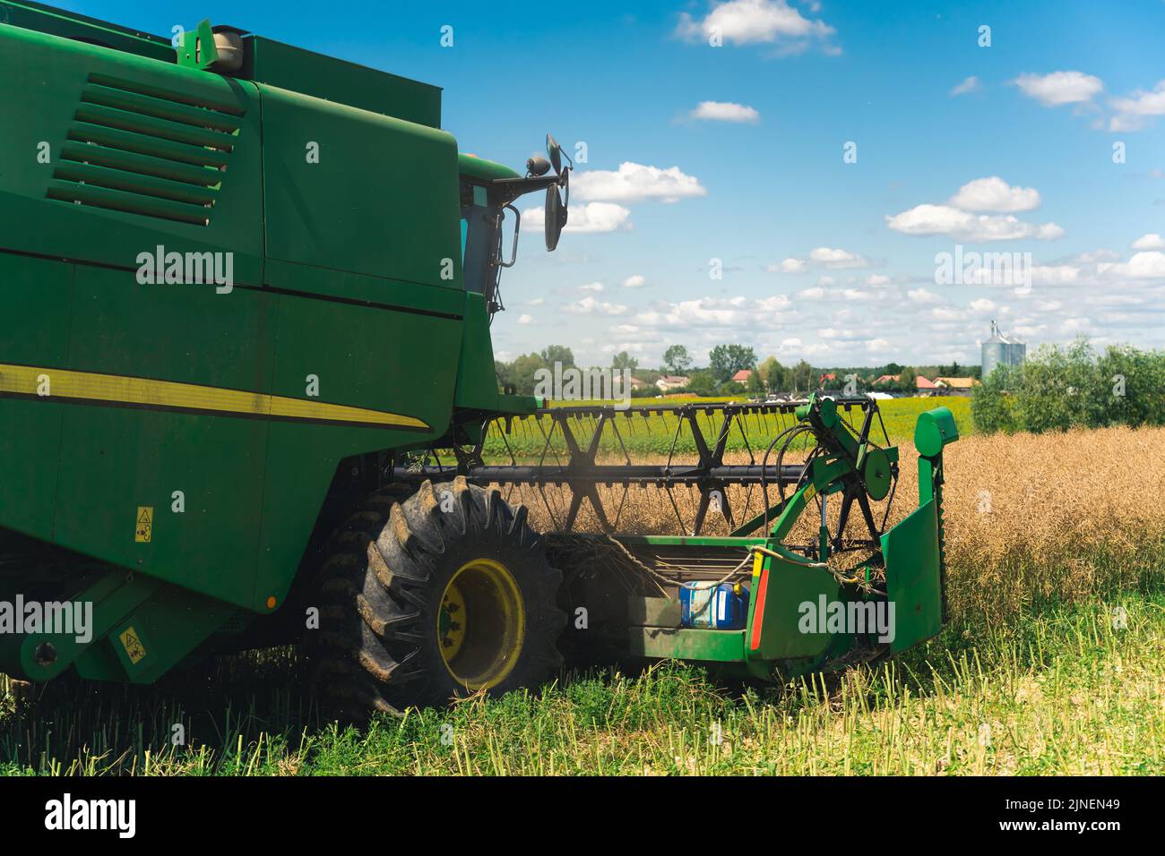 A big modern green combine harvester with a cutting bar or revolving ...