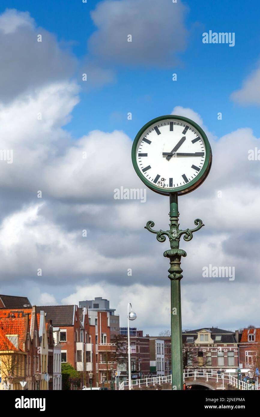 Street clock and traditional dutch houses against blue cloudy sky in ...