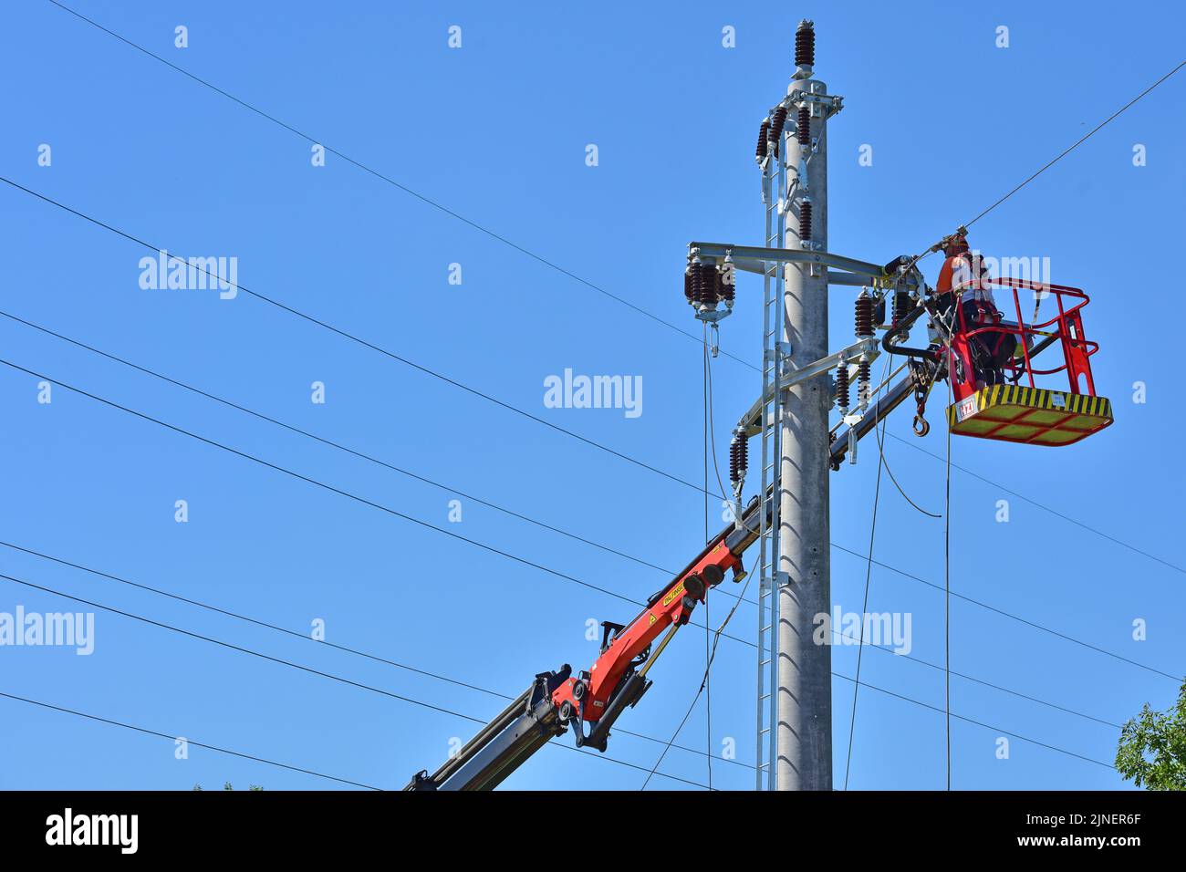 Freileitungsmonteur bei der Arbeit auf einem Strommasten ...