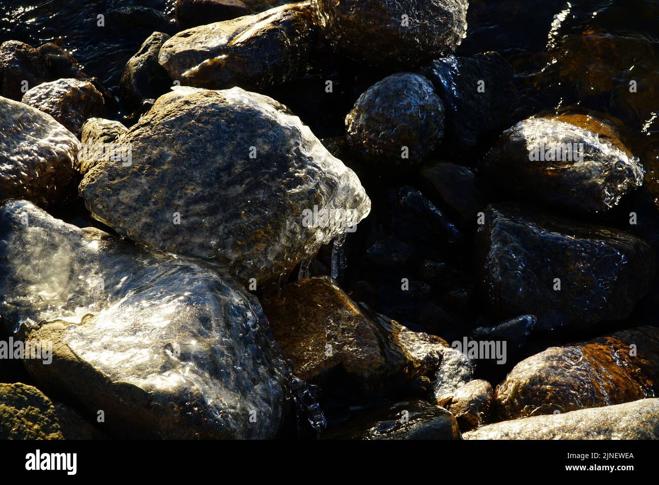A top view of frozen water on rocks in sunlight in winter Stock Photo ...