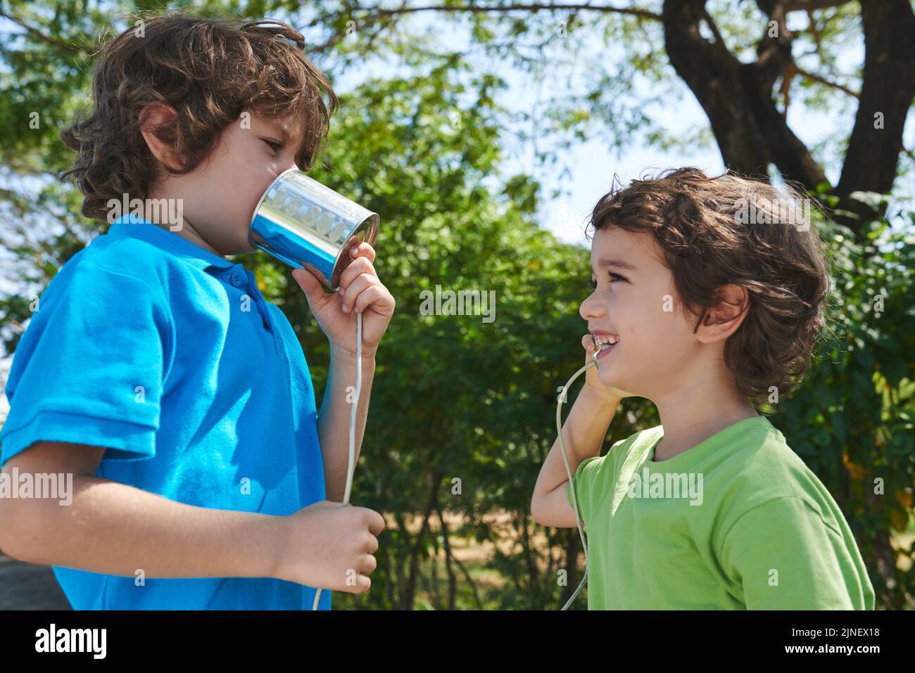 Happy children playing with tin telephone outdoors Stock Photo - Alamy