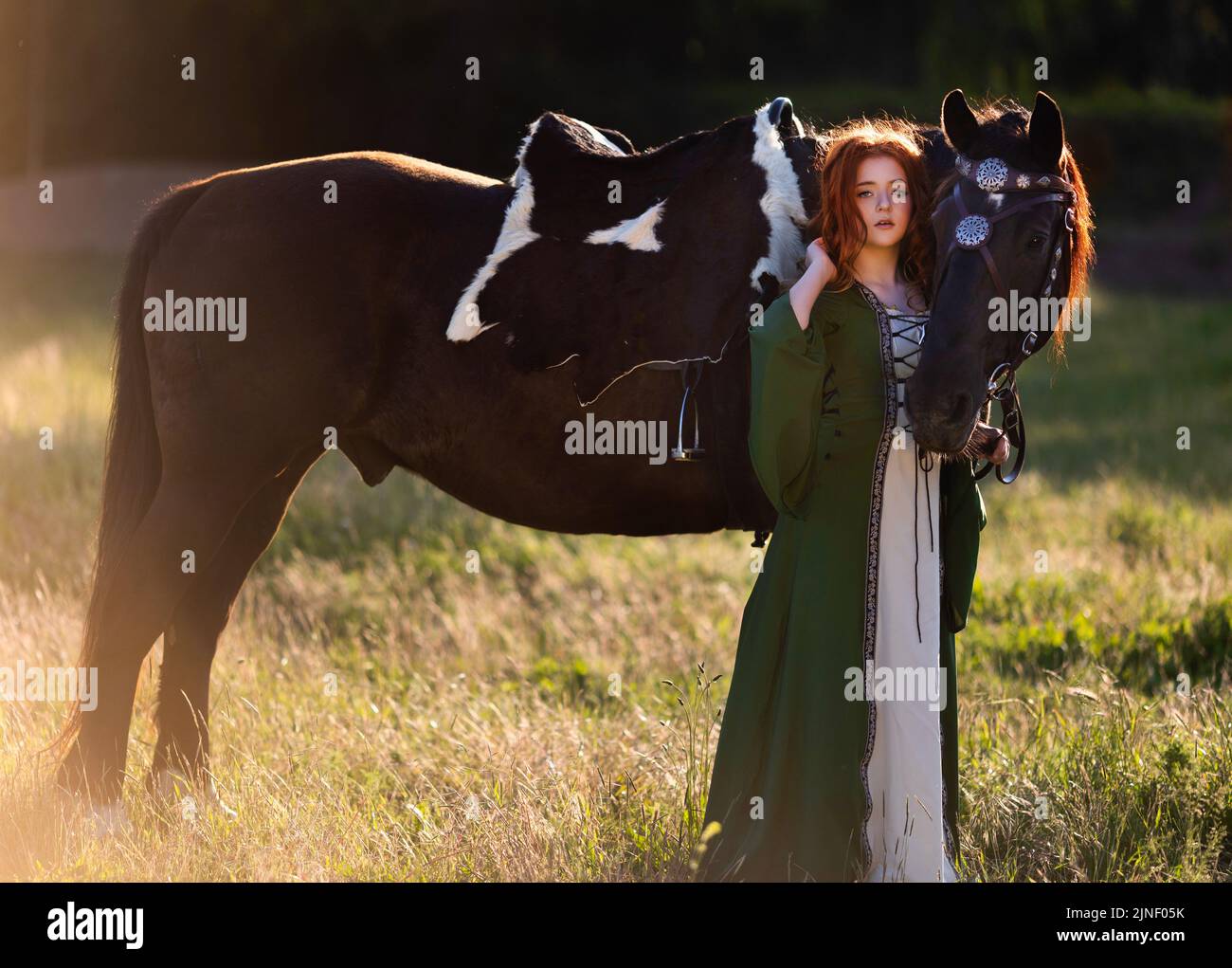 Medieval woman princess in green dress sits astride black steed horse ...