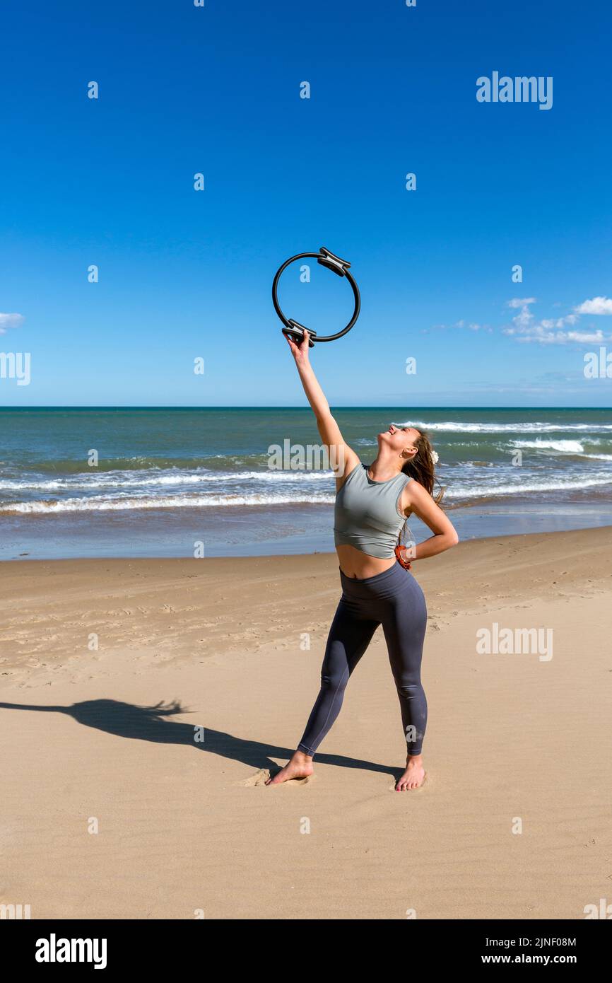young athlete posing with pilates ring on the beach Stock Photo - Alamy