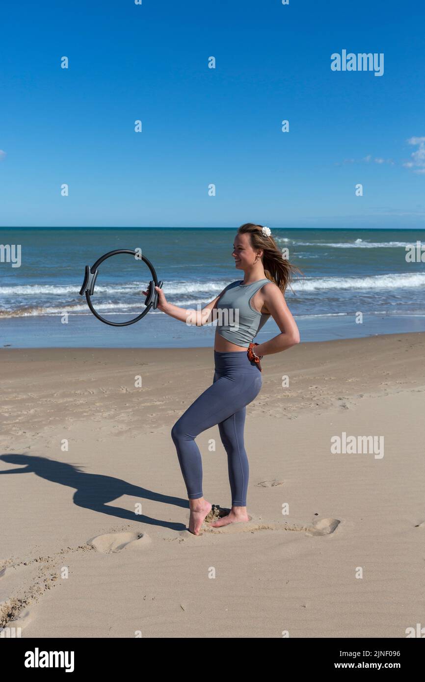 beautiful athlete posing with pilates ring at the beach Stock Photo - Alamy