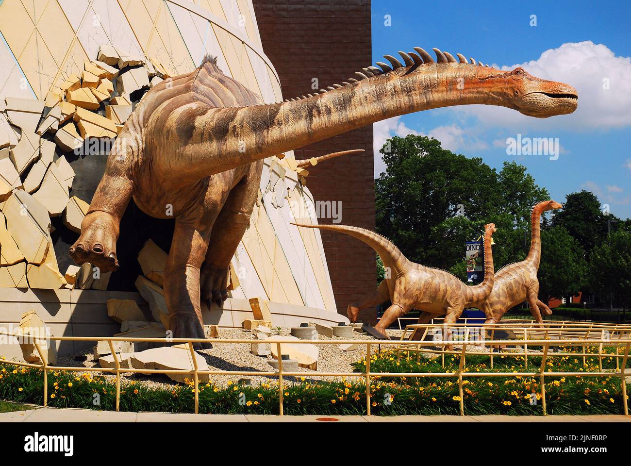 A group of dinosaurs appear to break out of the facade of the ...