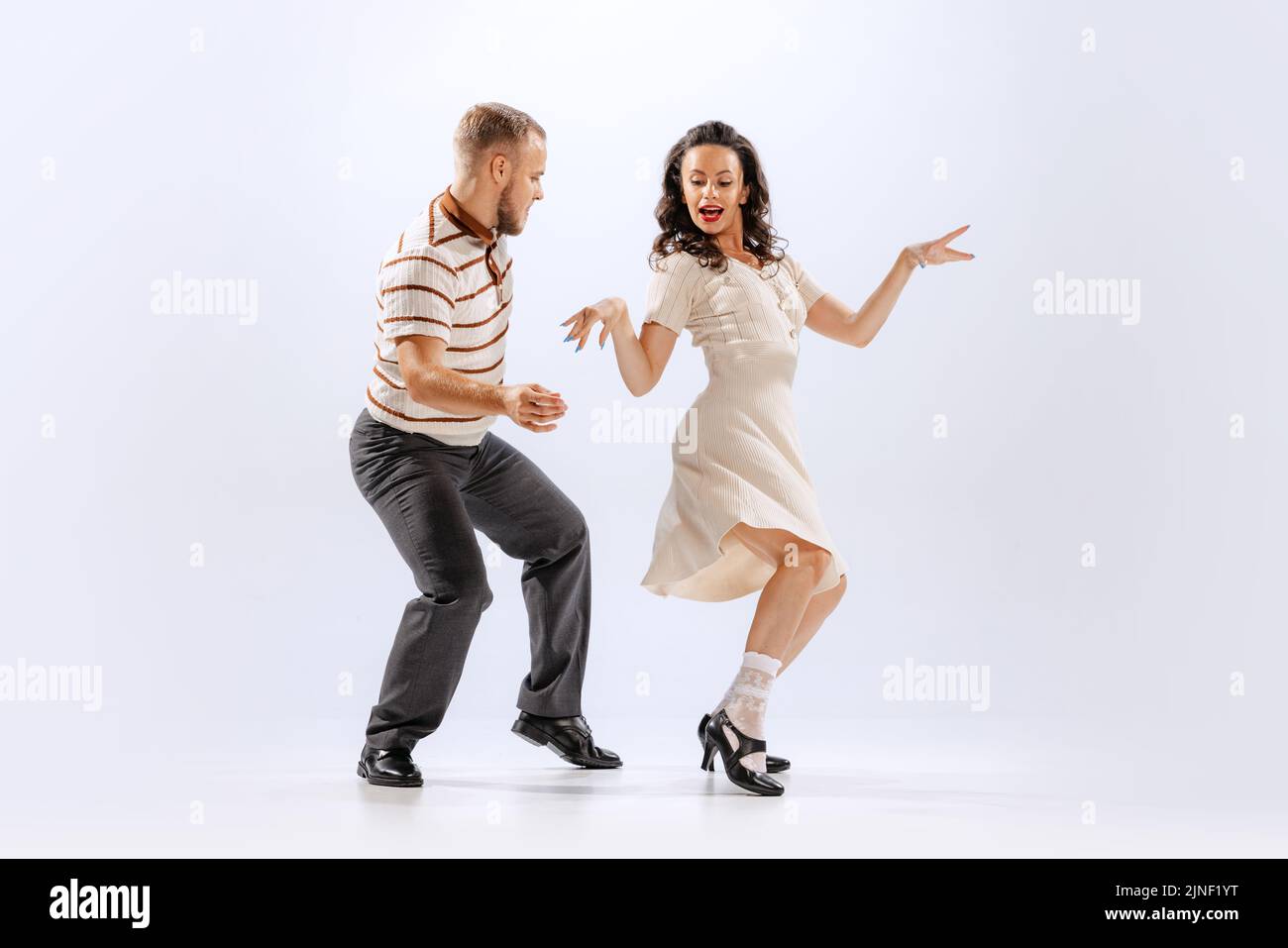 Excited young man and woman in retro style outfits dancing lindy hop ...