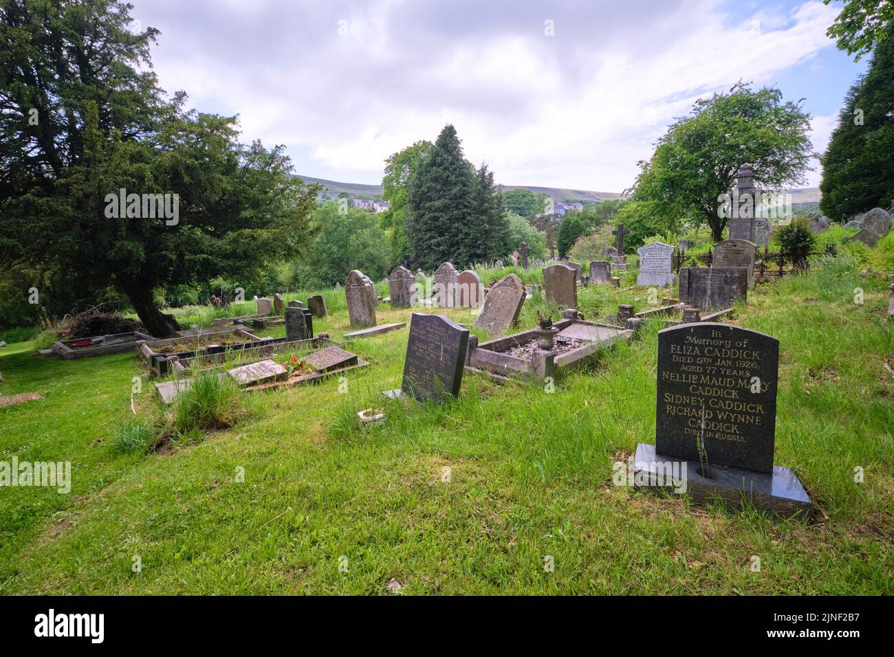 A hillside graveyard, cemetery with overgrown vegetation in the valley ...