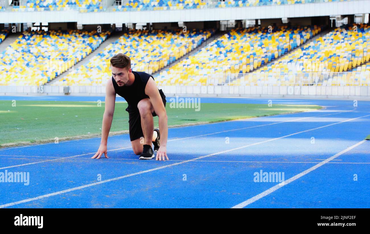 bearded man in sportswear and sneakers standing at starting pose before ...