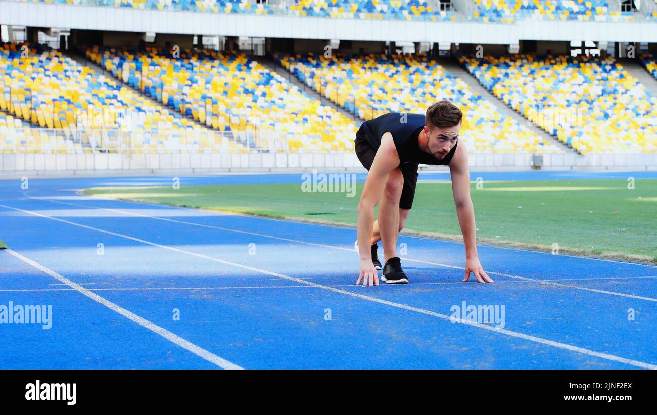 bearded man in sportswear standing at starting pose before running at ...