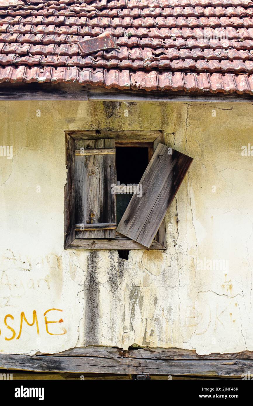A dilapidated house with broken windows, wooden shutters hanging off ...