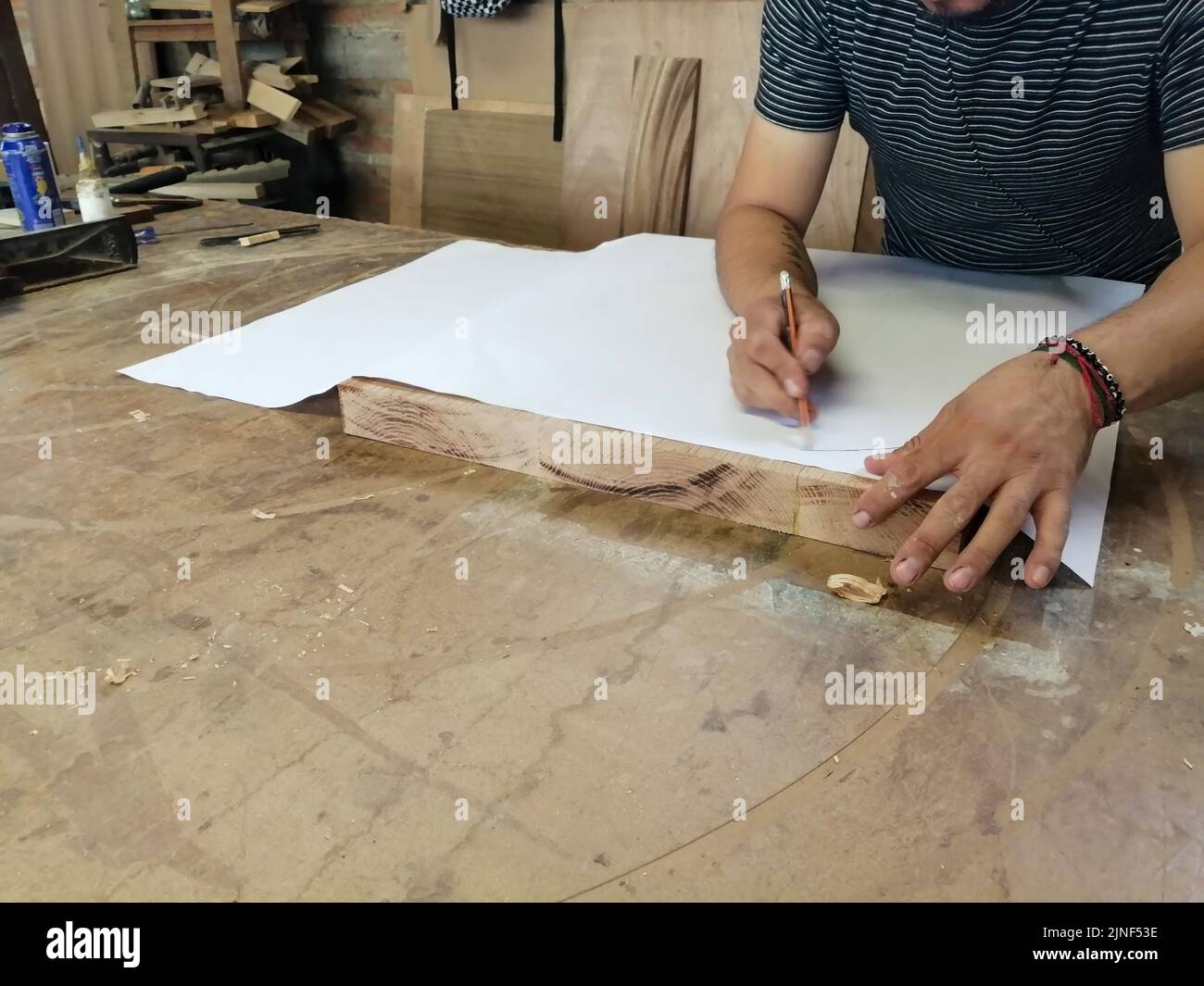 A carpenter working on a new project at his workshop, drawing on a ...