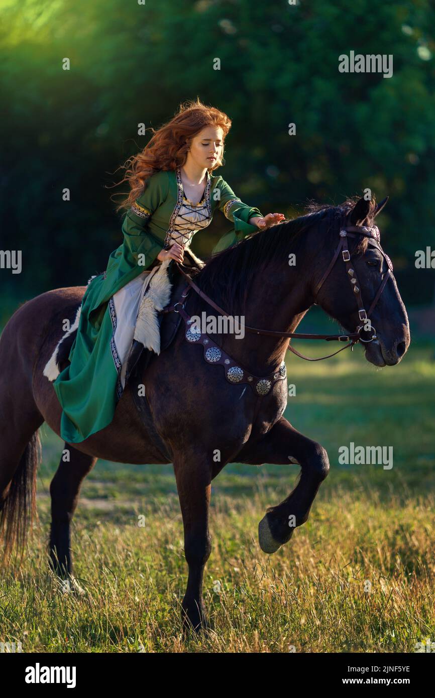 Medieval woman princess in green dress sits astride black steed horse ...