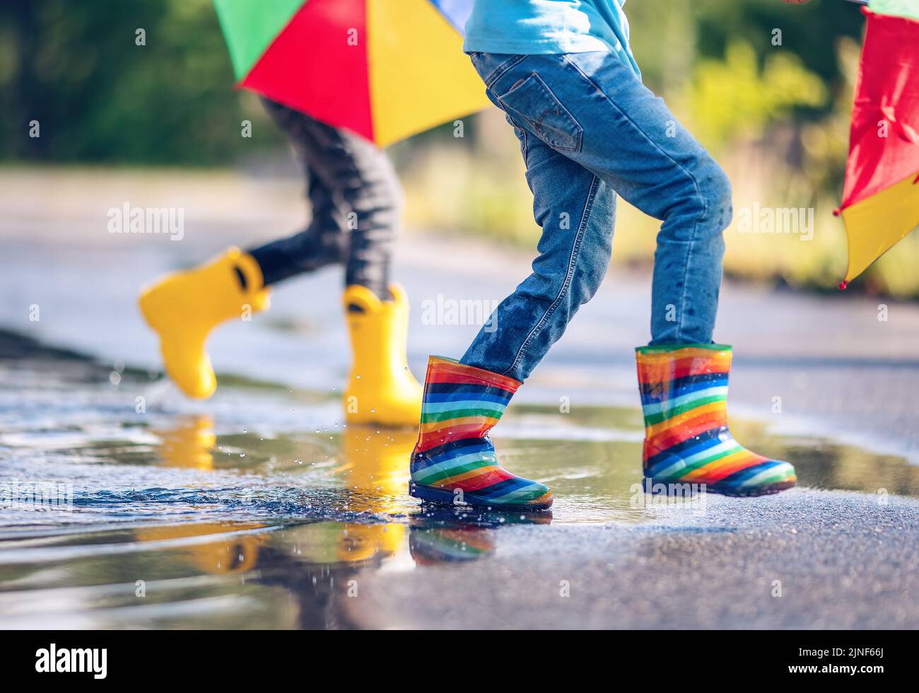 Children jumping in the puddle in rubber boots Stock Photo - Alamy