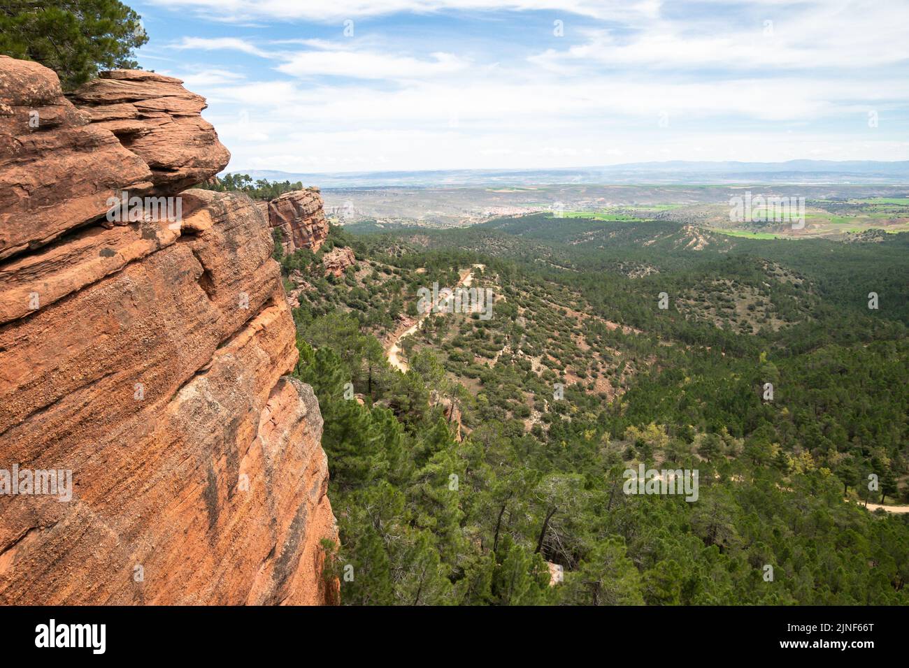 Landscape looking over forested plain at the base of a red sandstone ...