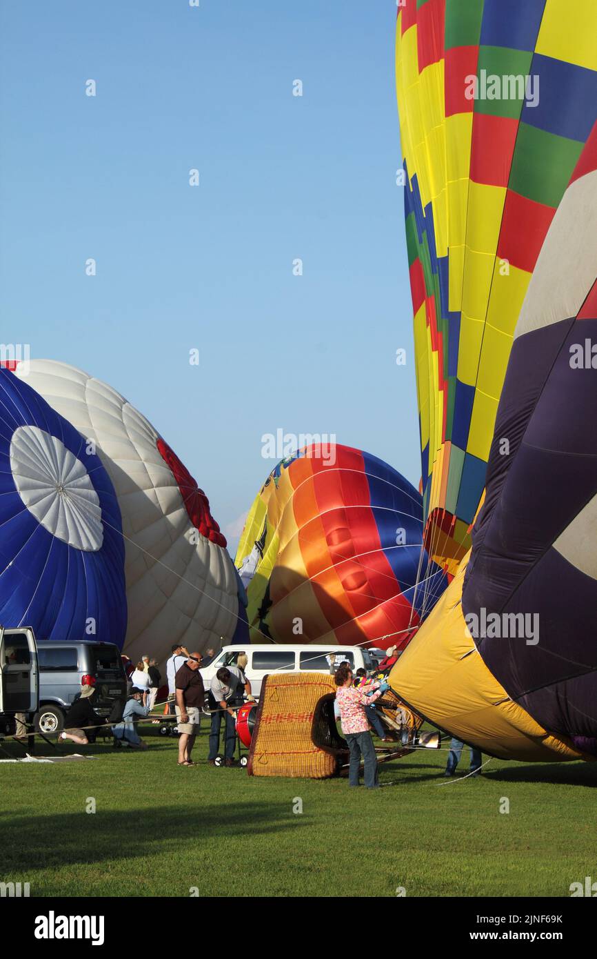 A vertical shot of people blowing up balloons at a hot air balloon ...