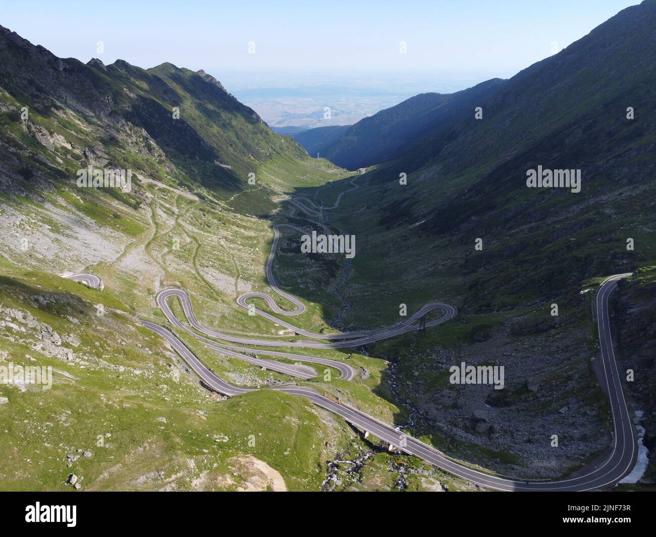 An aerial view of complex switchback roads in a green mountainous ...