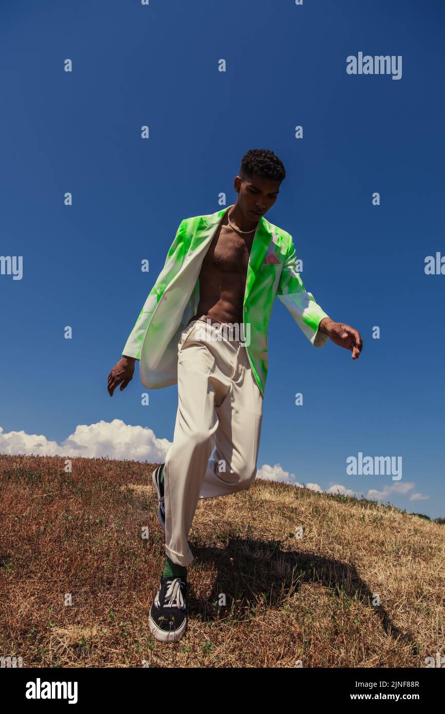 full length of trendy african american man running in field on summer ...