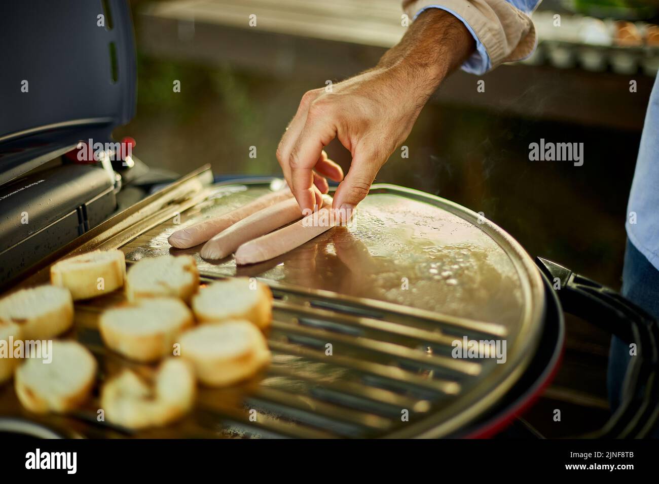 Close up on man's hand put sausages and roasting bruschetta on the ...