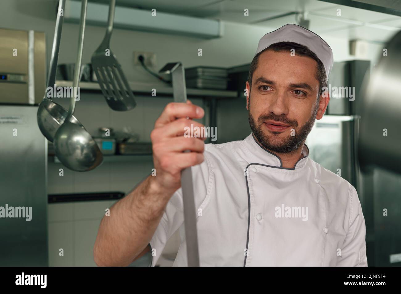 Chef cooking tasty dish in kitchen of restaurant using modern equipment ...