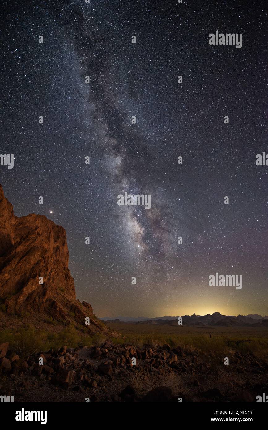 A vertical mysterious view of a milky way over the rocks and field ...