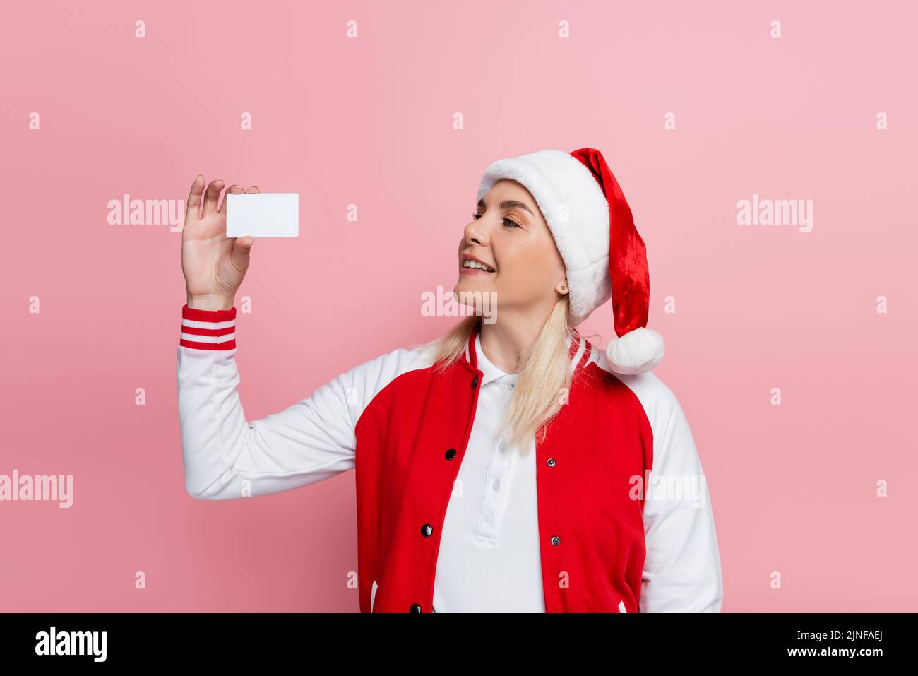 Smiling blonde woman in santa hat holding empty driving license ...