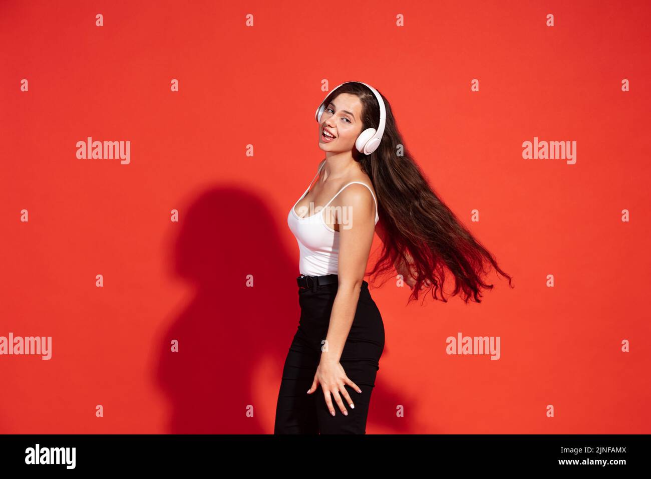 Portrait of cheerful young woman, student posing in headphones isolated ...