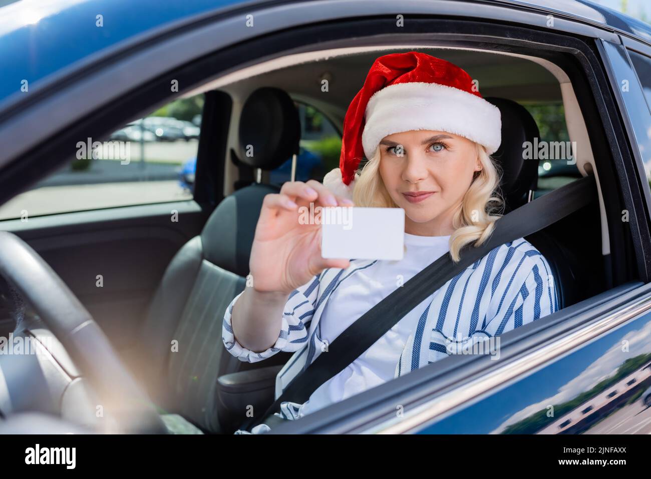 Blonde woman in red santa hat holding driving license in auto,stock ...