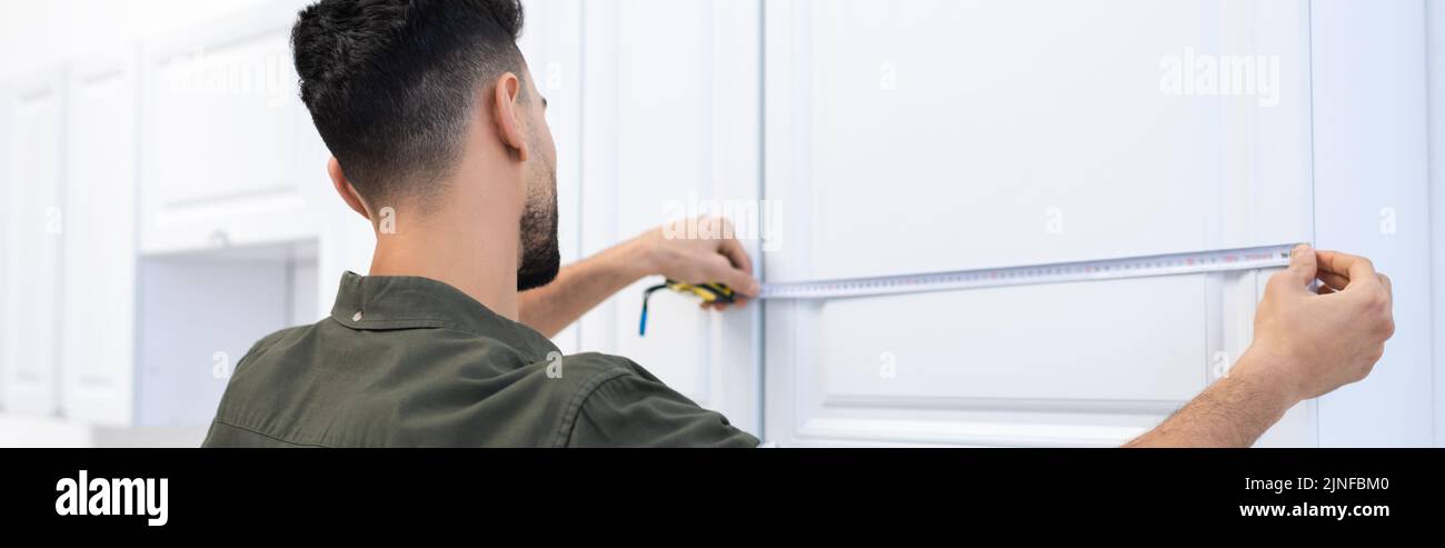 Arabian man with tape measure measuring kitchen cabinet, banner,stock ...