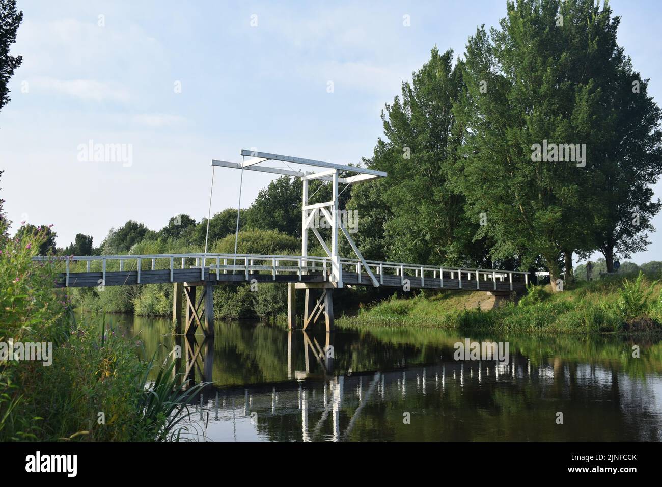 A landscape view with a white drawbridge over a river Stock Photo - Alamy