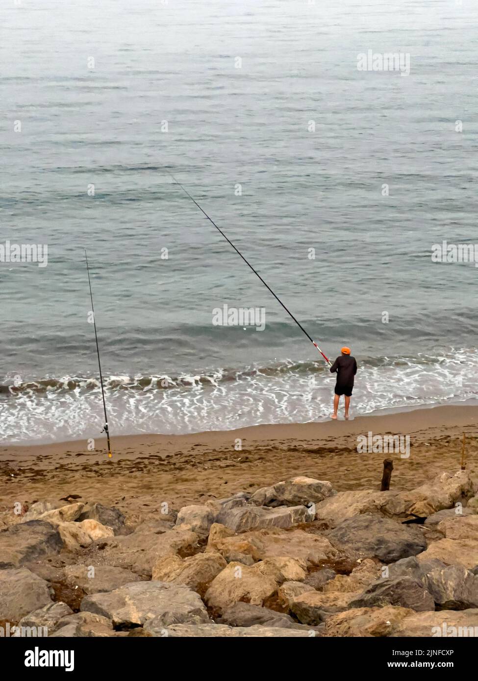 Fisherman standing on the beach and trying to catch some fish Stock ...