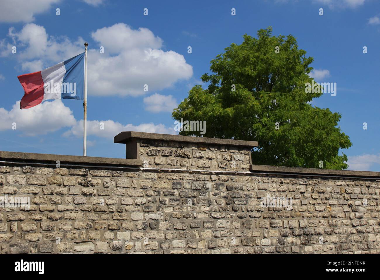 French flag flying above a stone wall on a sunny summers day with a ...