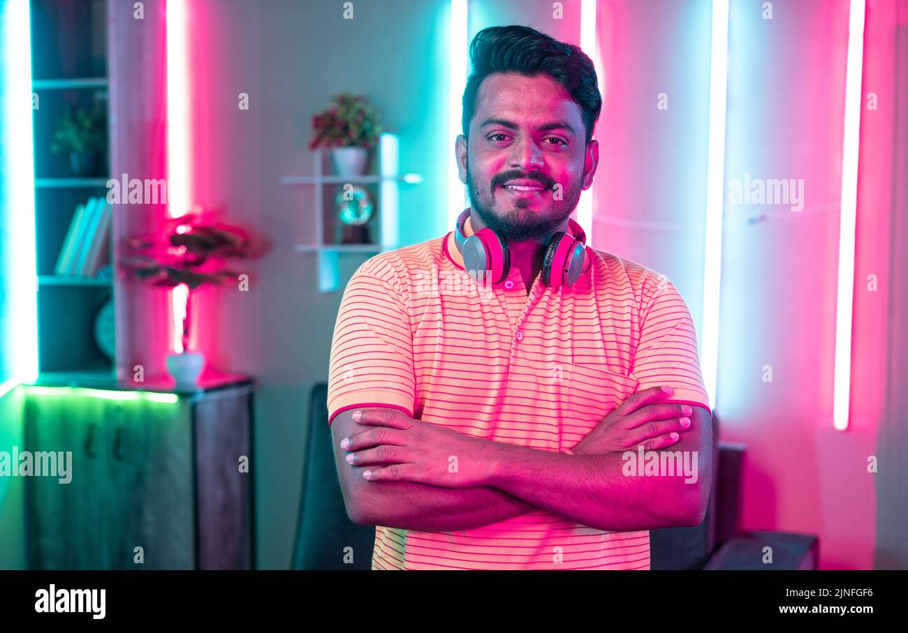 Happy smiling professional gamer standing with arms crossed by looking ...