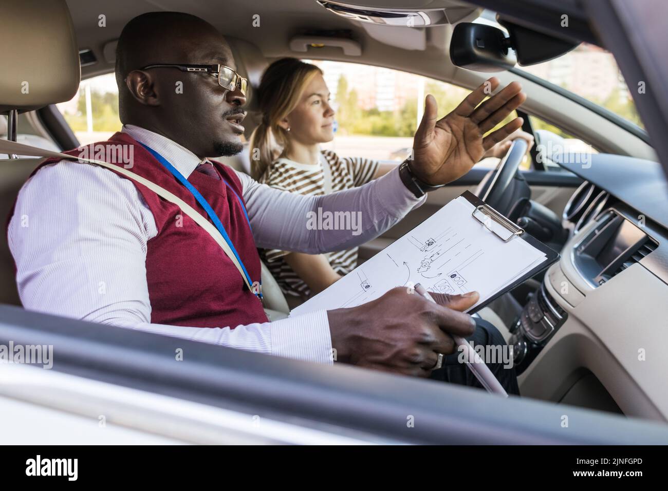 Driving school concept. A car instructor teaches a young woman how to ...