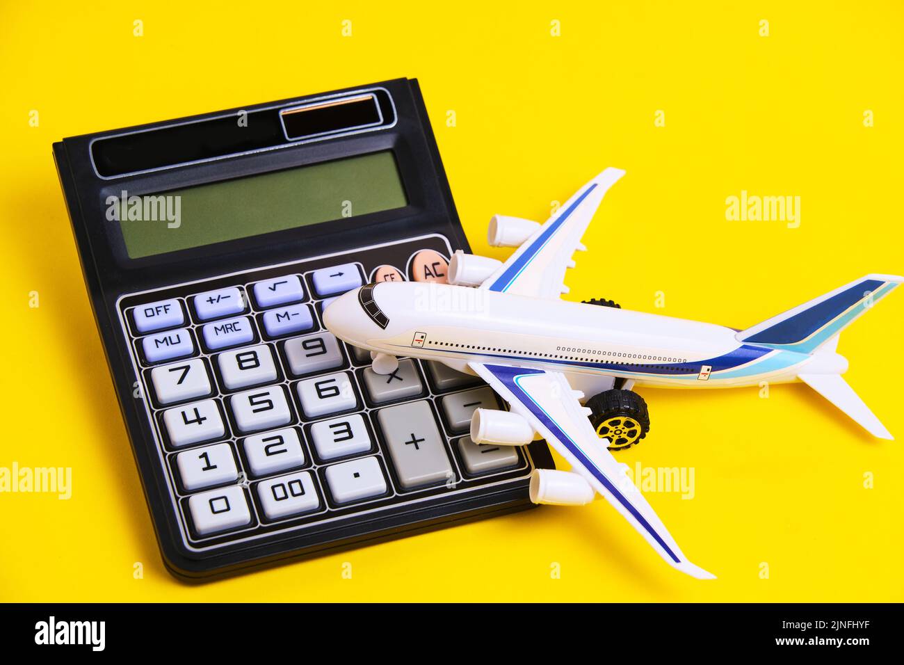 Airplane model and calculator yellow background.Concept of costs or ...