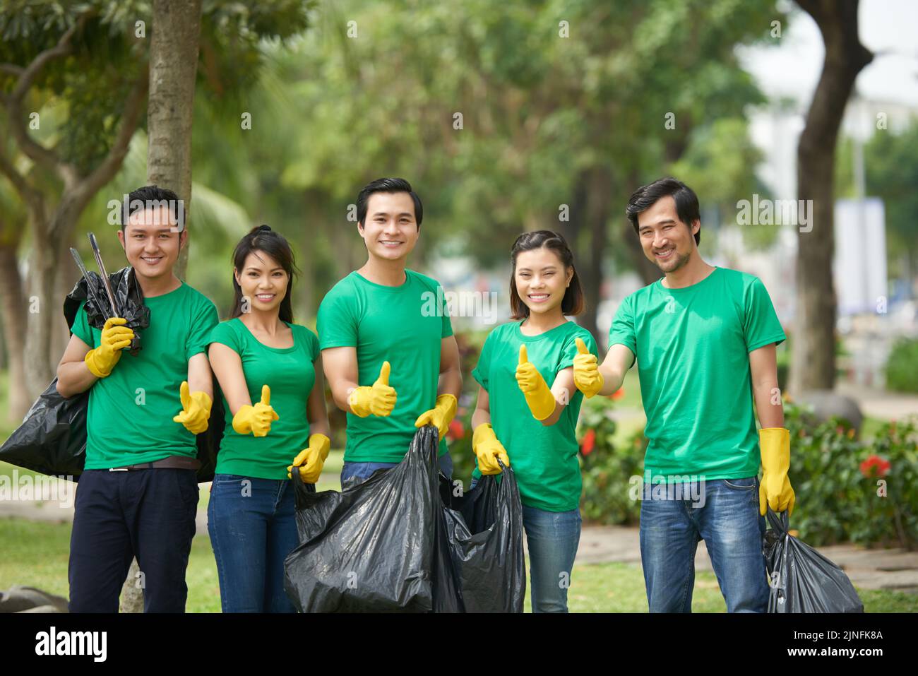 Cheerful environmental volunteers with full trash bags after cleaning ...