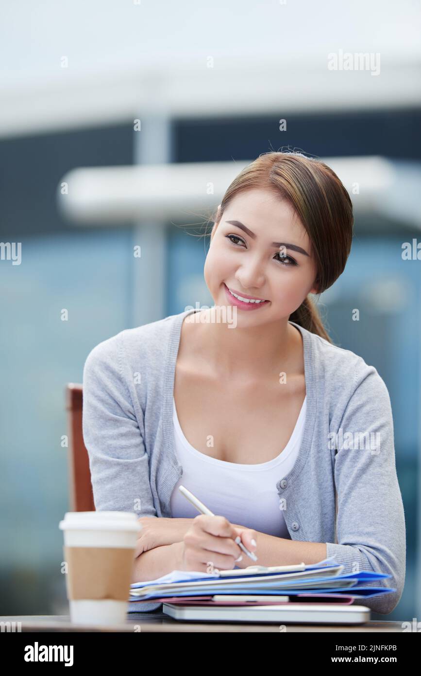 Portrait of attractive young business woman writing plans in her ...