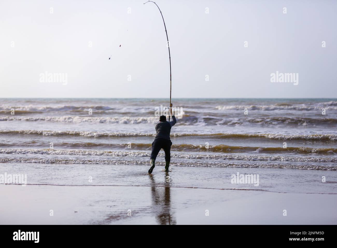A Fisher man throwing his hook with his fisher rod Stock Photo - Alamy