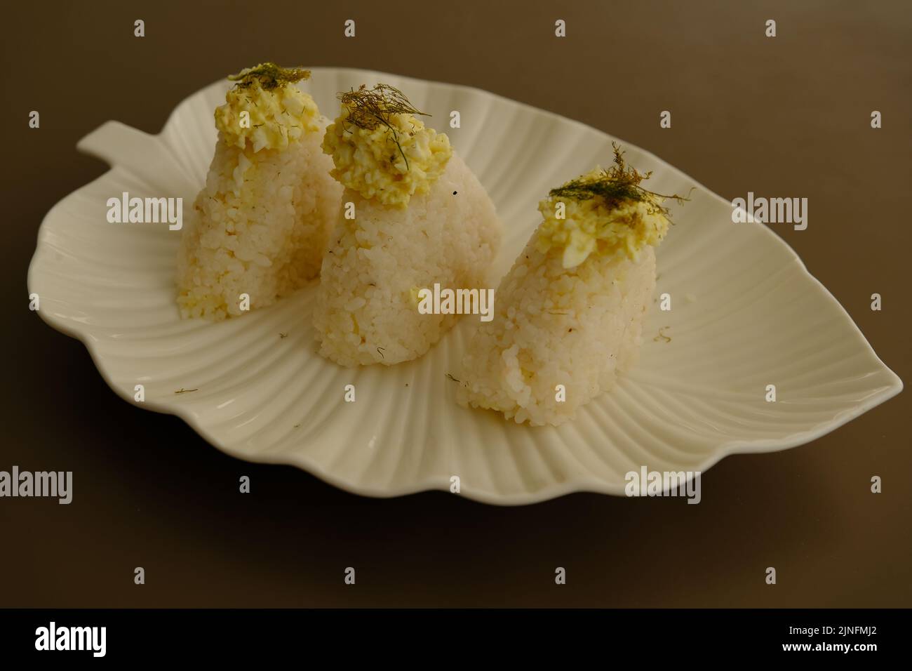 Plate with traditional Japanese onigiri with egg on brown background ...