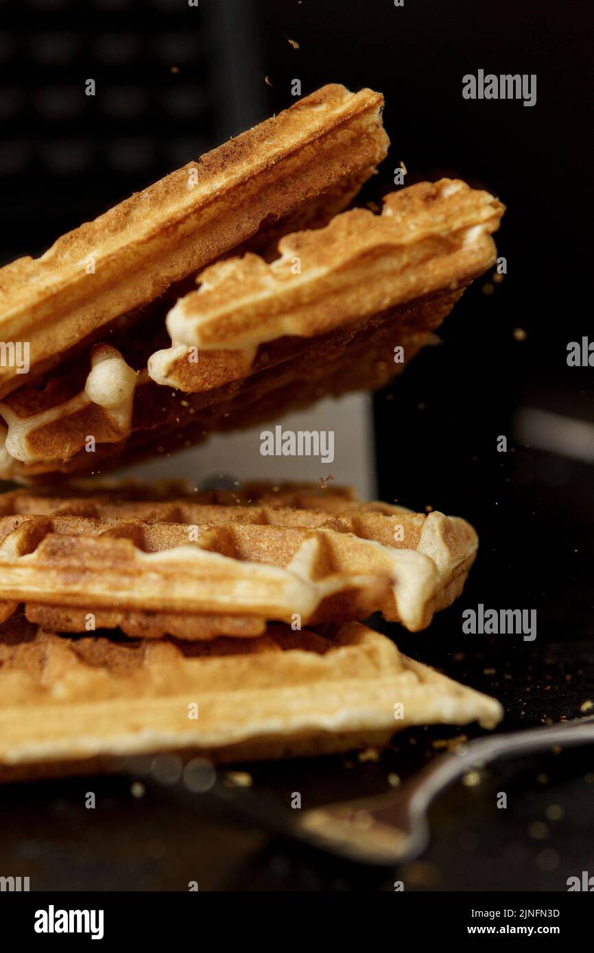 A vertical shot of crispy waffles thrown on top of each other with ...