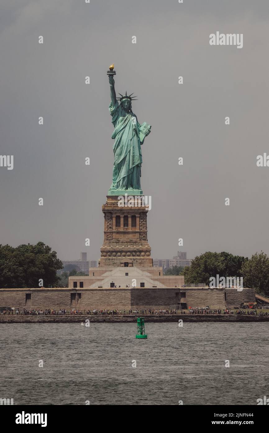 A beautiful view of the statue of Liberty against a dark grey sky in ...